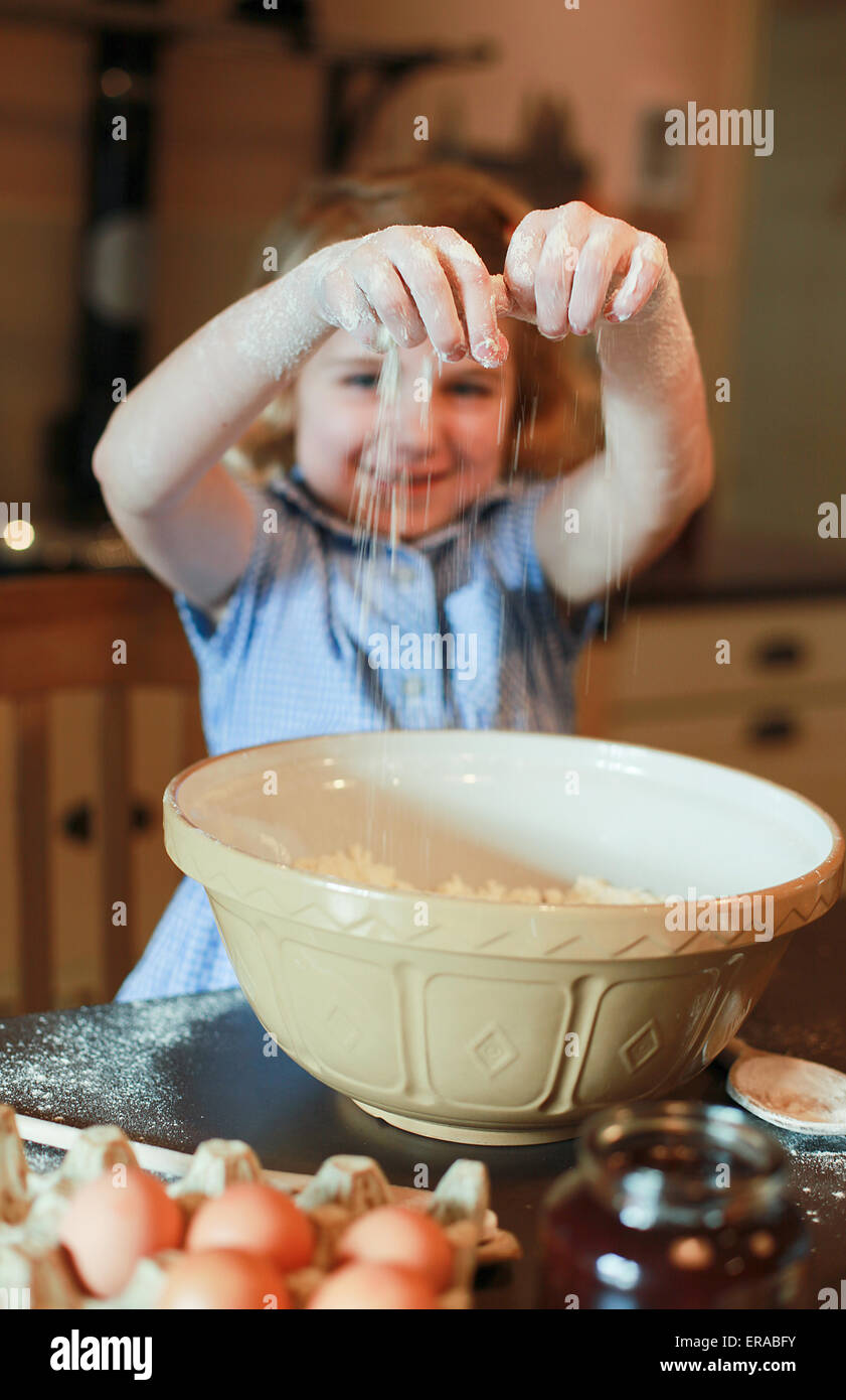 Pretty blond haired girl baking wearing checked dress Stock Photo - Alamy