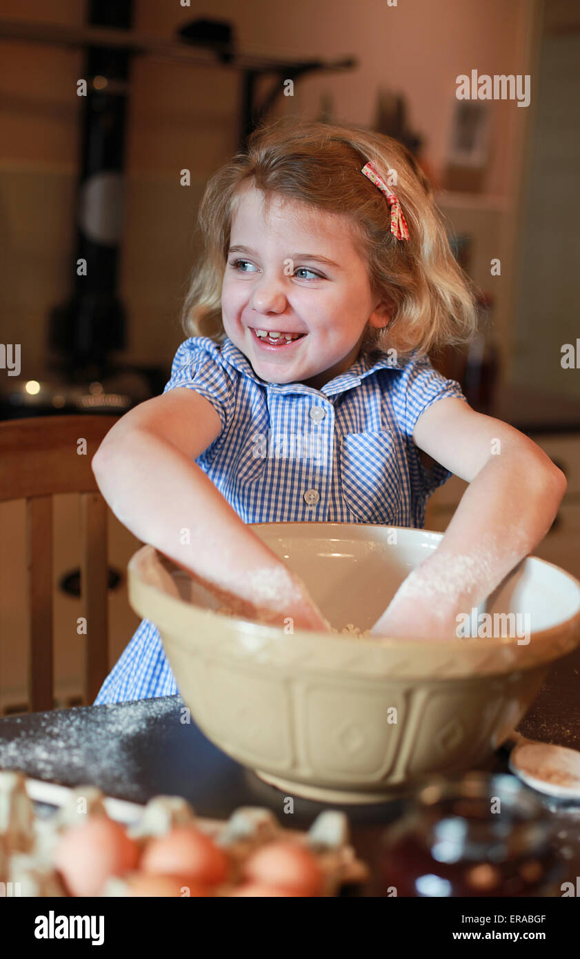 Pretty blond haired girl baking wearing checked dress Stock Photo - Alamy