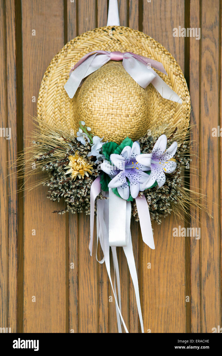 decorative hay hat with flowers and ribbon on wooden door Stock Photo ...