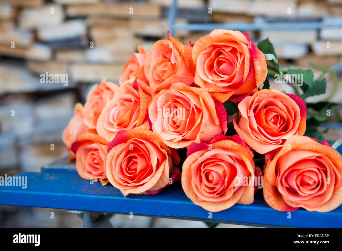 orange roses on a blue rustic chair in front of stack of wood Stock ...