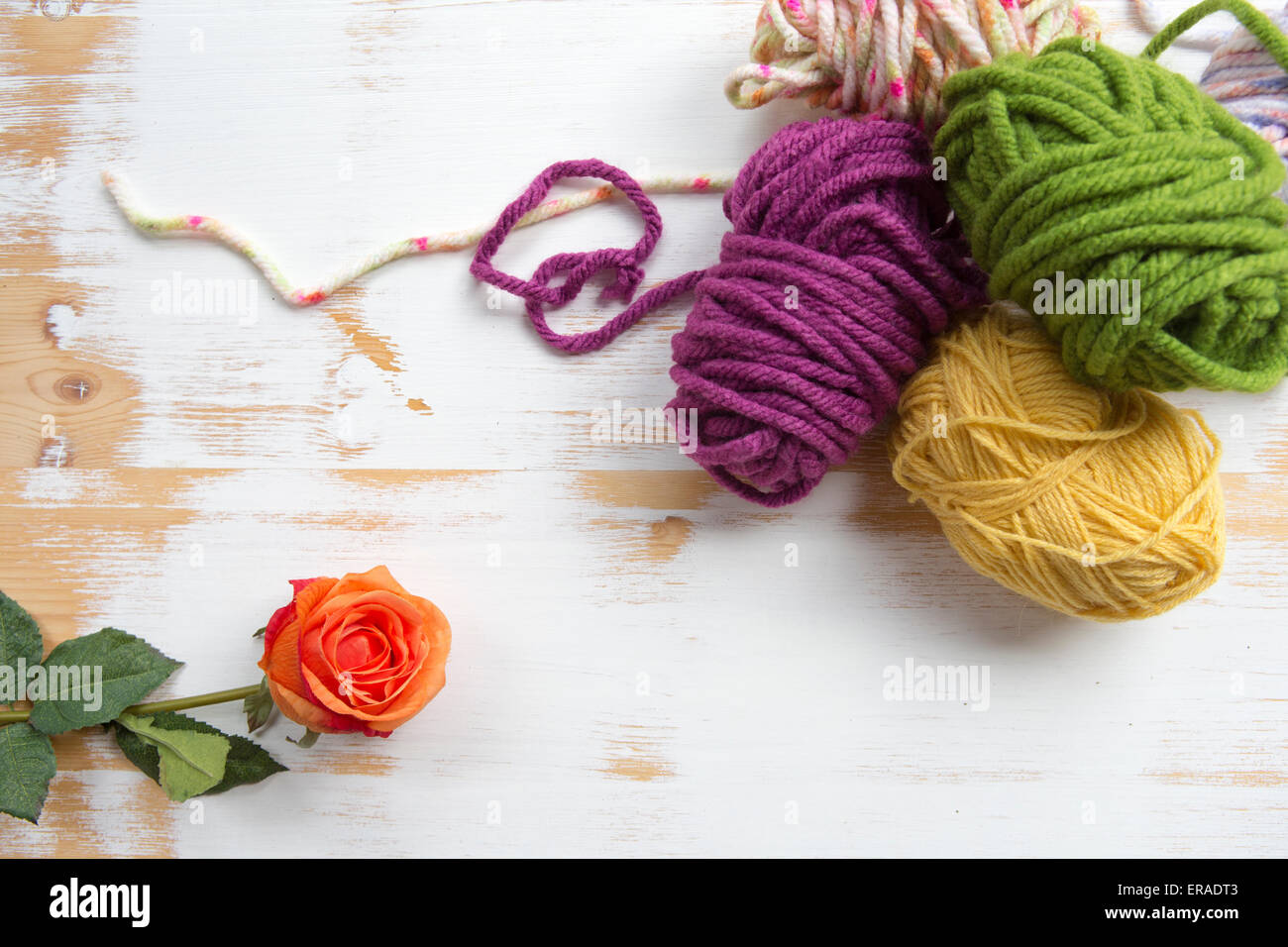 colorful balls of wool on rustic white wooden background with an orange ...