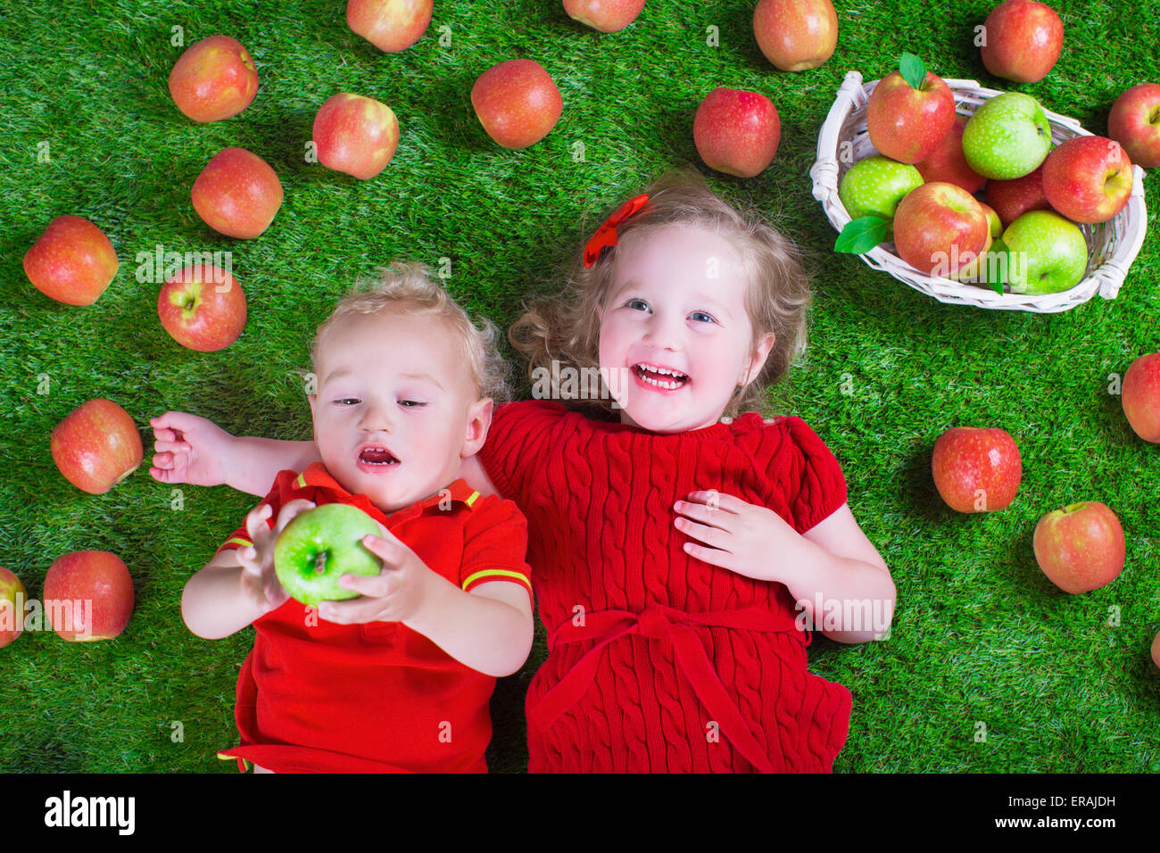 Child eating apple. Little girl and baby boy play peek a boo holding ...