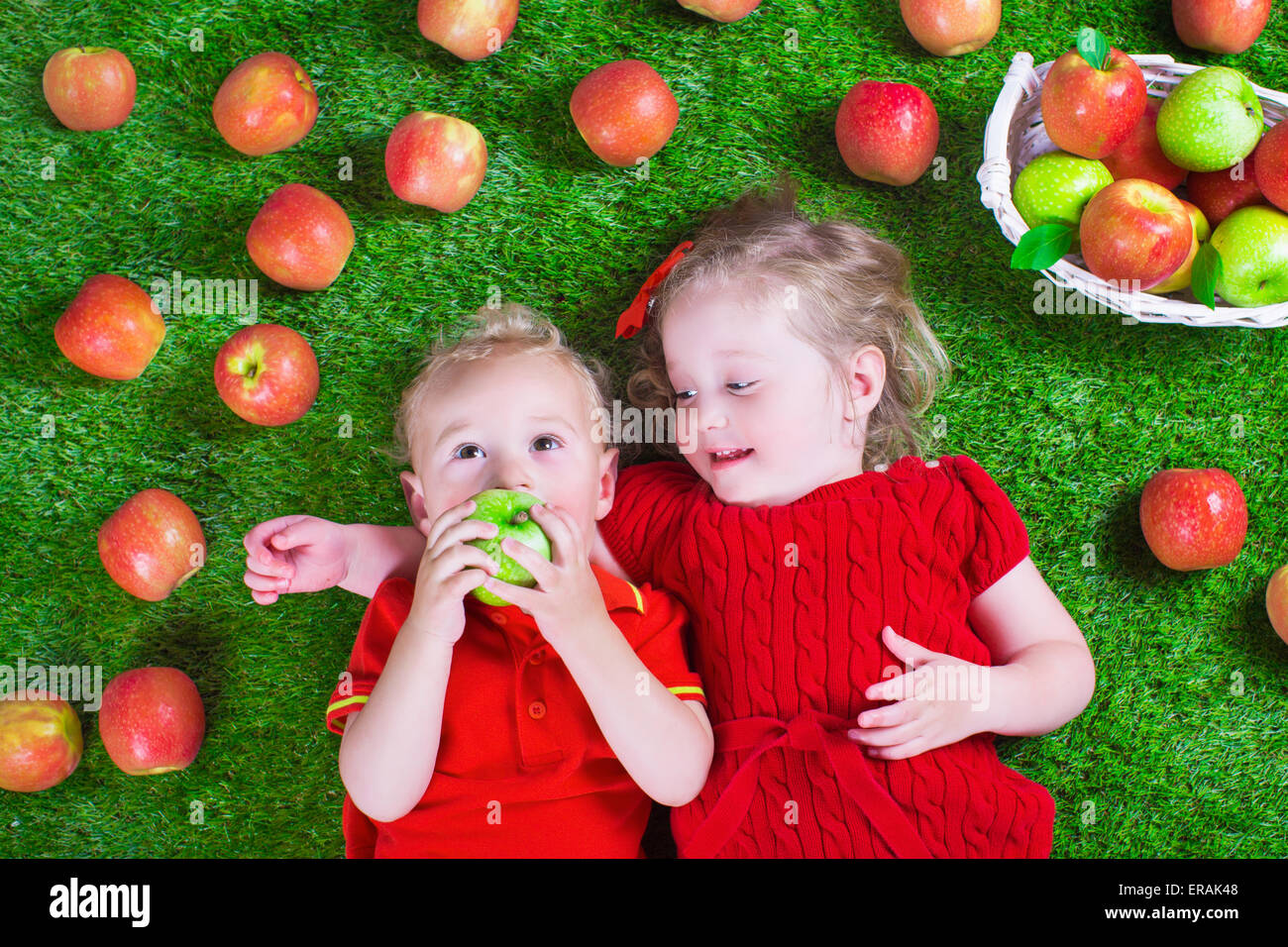 Child eating apple. Little girl and baby boy play peek a boo holding ...