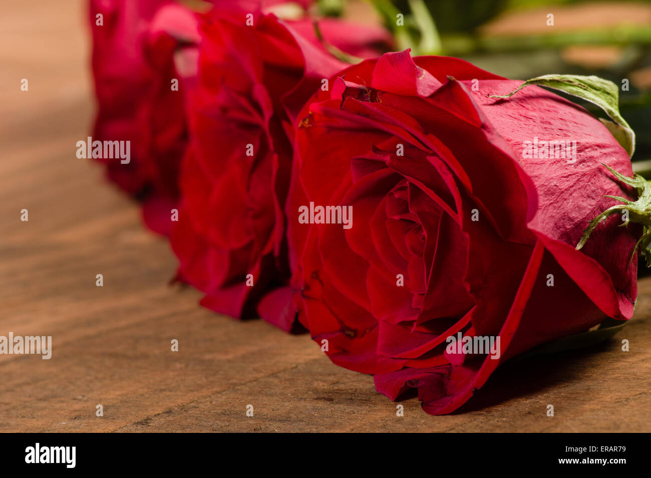 Bright red roses on a rough wooden table Stock Photo - Alamy