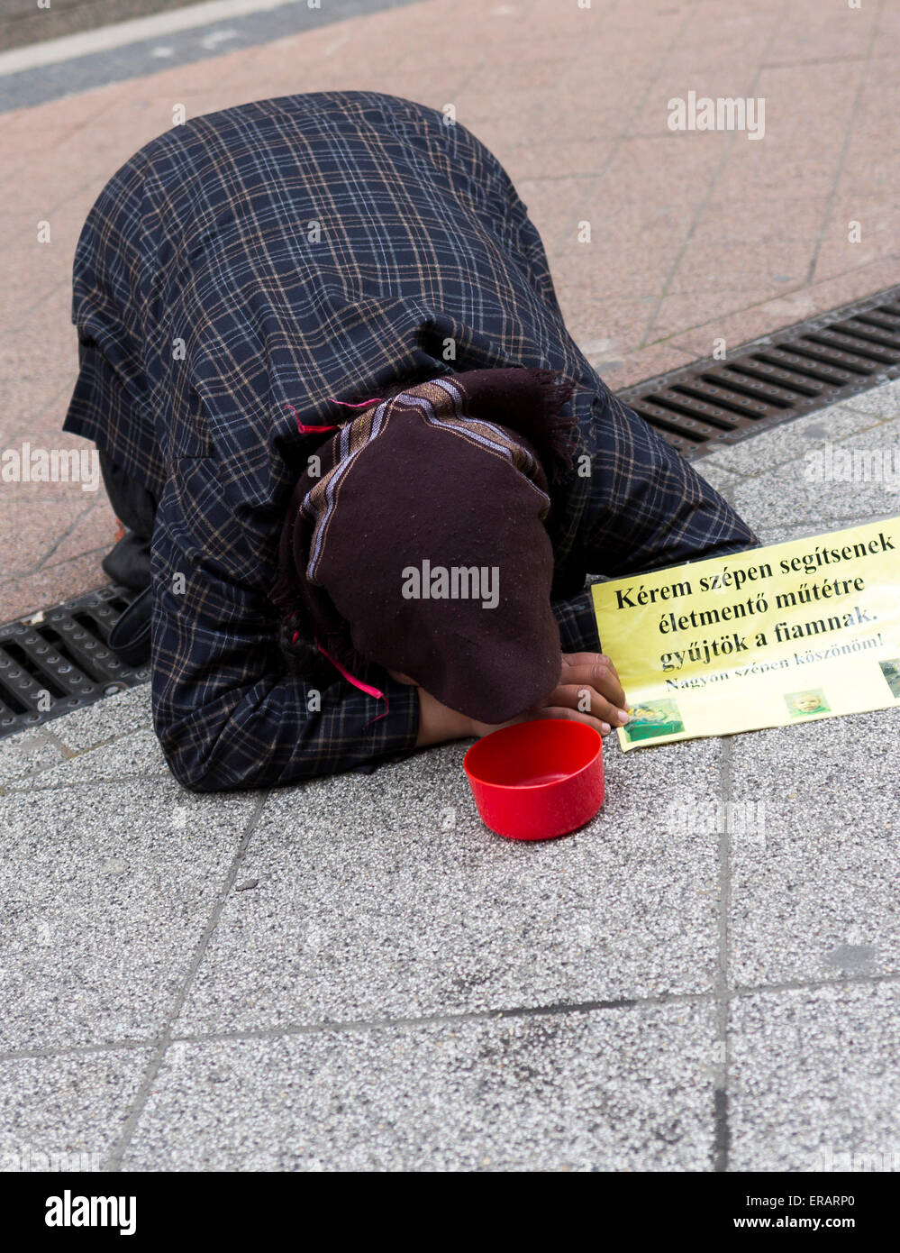An old woman is begging on the ground of a main street in Budapest ...