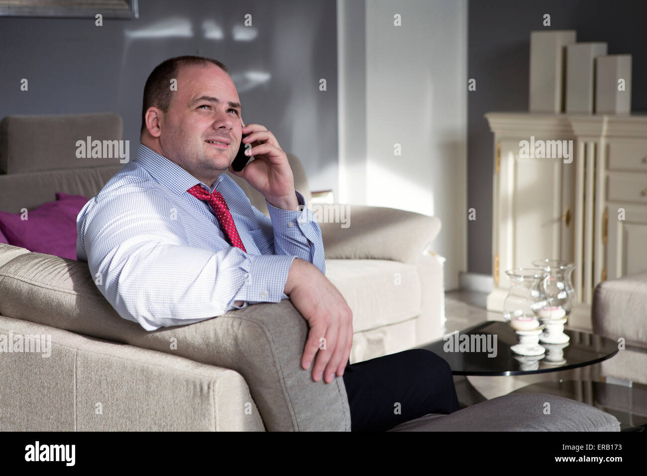 fat man in shirt and tie sits on couch and talks on the phone Stock ...