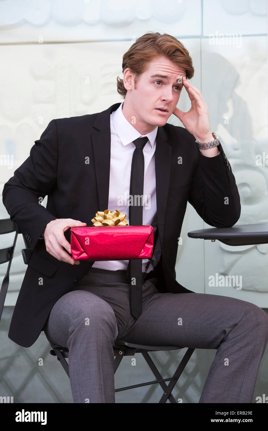 man in a suit sitting and waiting with a gift in his hand Stock Photo ...