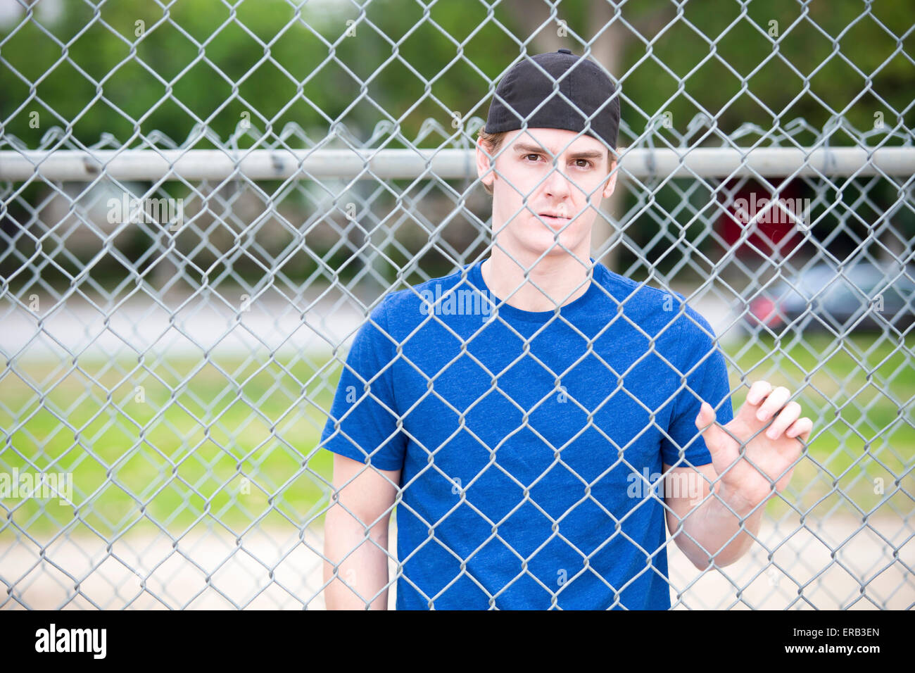 young man standing behind a fence Stock Photo - Alamy