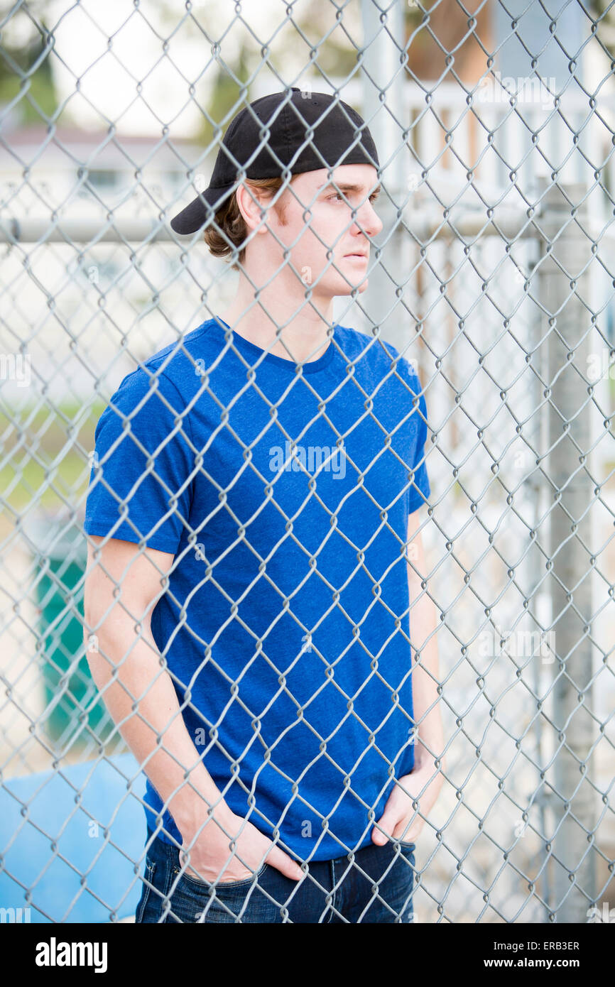 young man standing behind a fence Stock Photo - Alamy