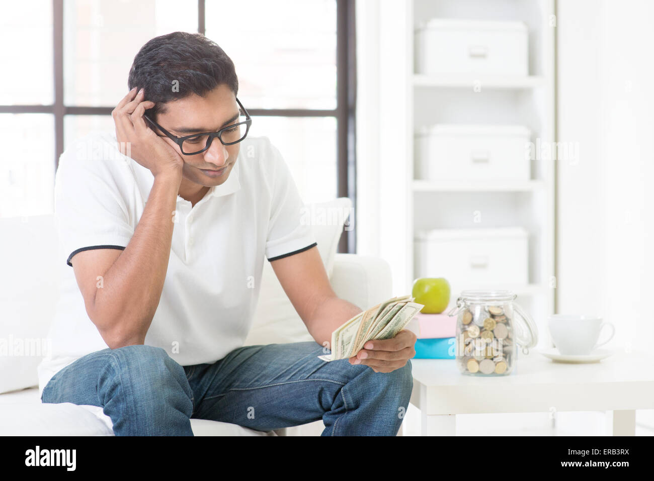 Financial problems concept. Indian guy counting money with sad ...