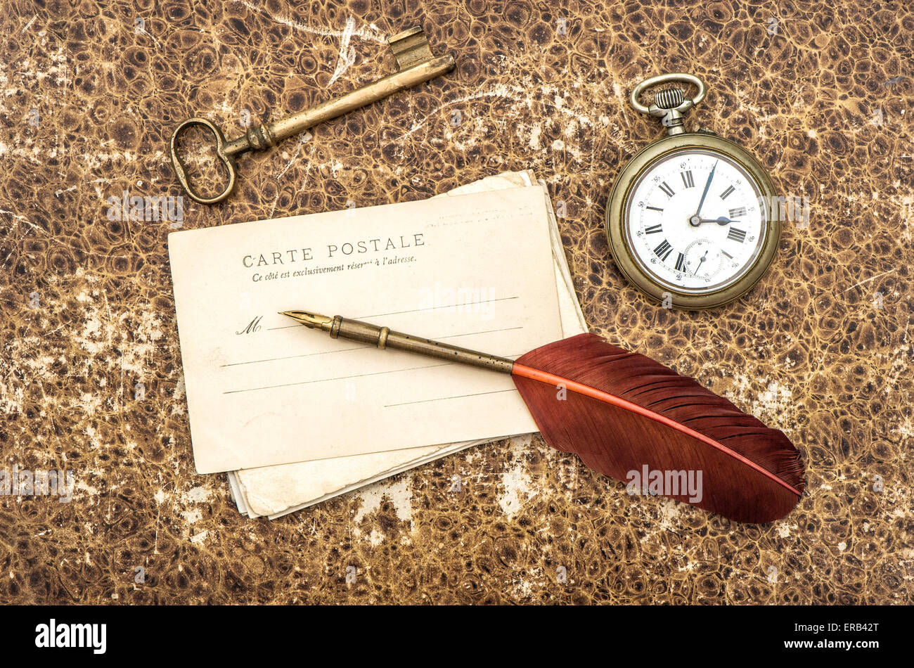 Vintage still life with old postcards, pocket watch, key and feather ...