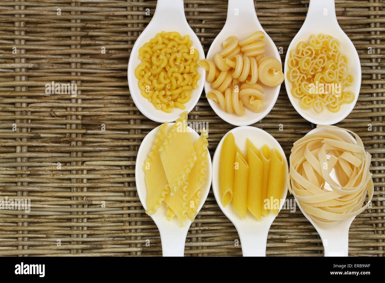 Pasta on porcelain spoons on wicker surface with copy space Stock Photo ...