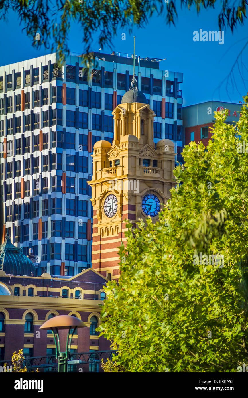 Close up of Flinders Street Station clocktower against office buildings ...