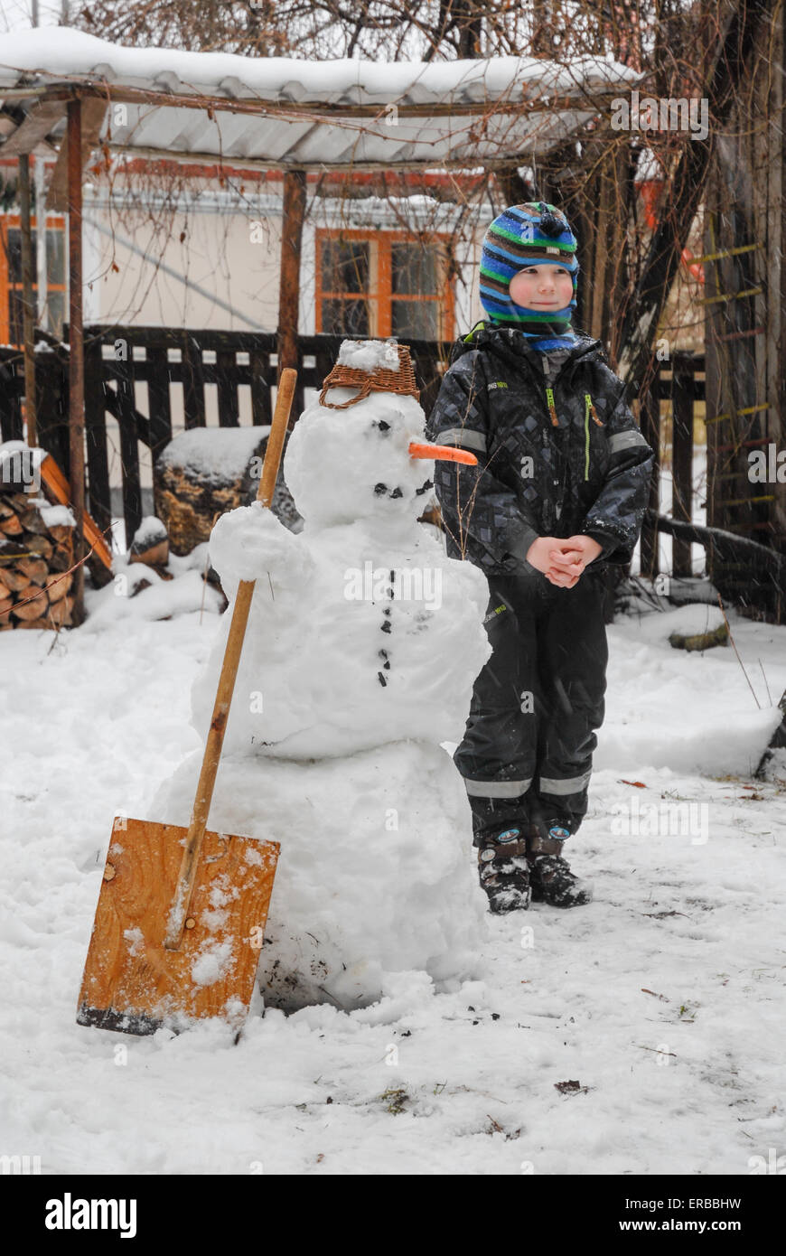 Traditional snowman with six years old boy and snow shovel Stock Photo ...