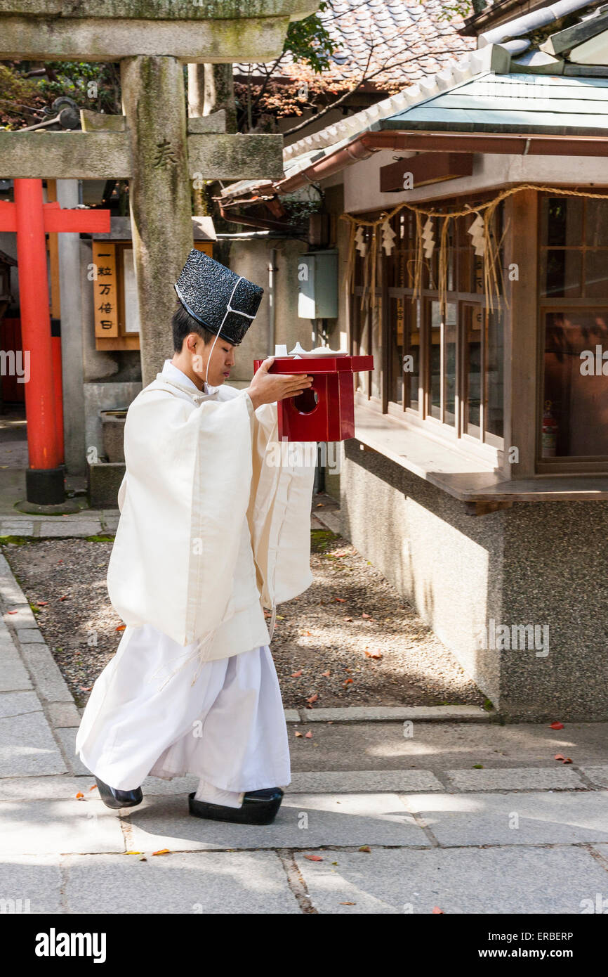 A Shinto priest, Shinshoku, wearing a white robe, Joe, walking out of a ...