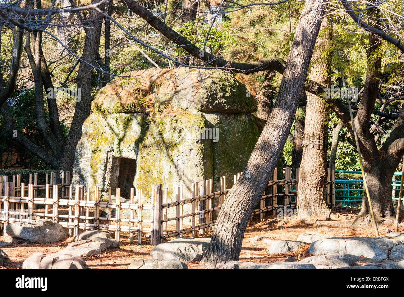 Small stone moss covered storehouse with wooden fence around it among ...