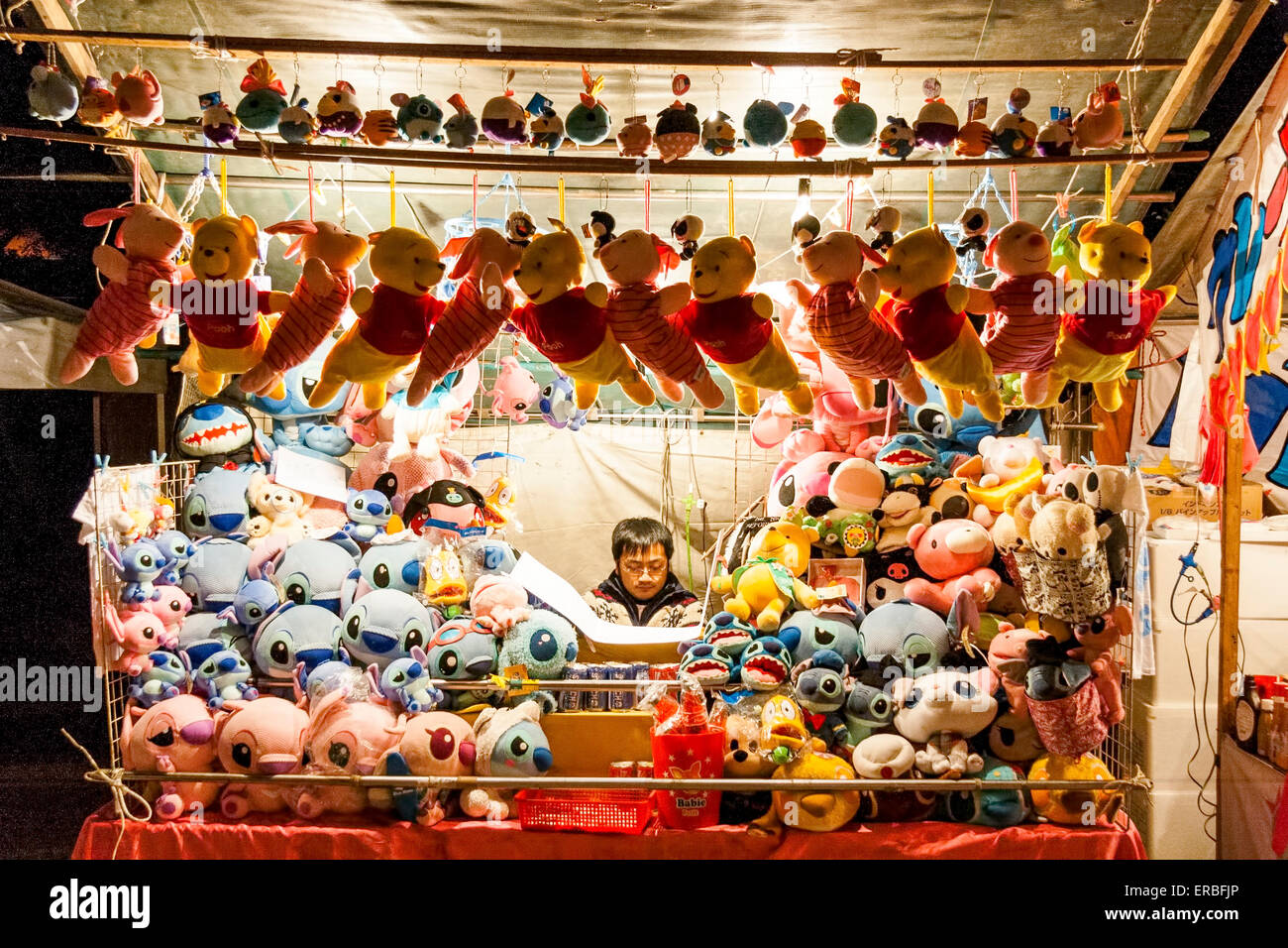 Man, stall owner, sitting asleep surrounded by hundreds of stuffed ...