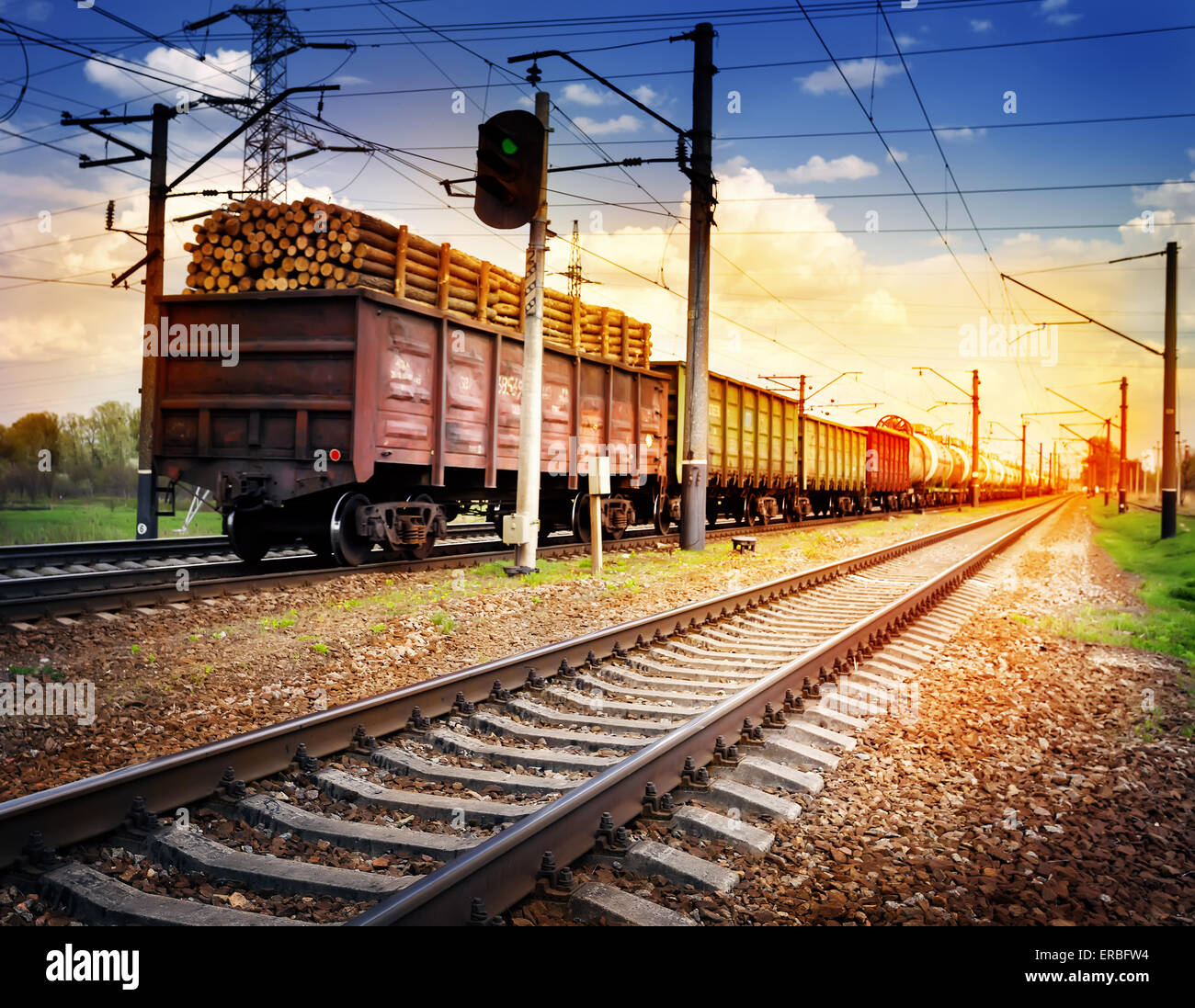 Railway with freight train receding into the distance to the sun Stock ...