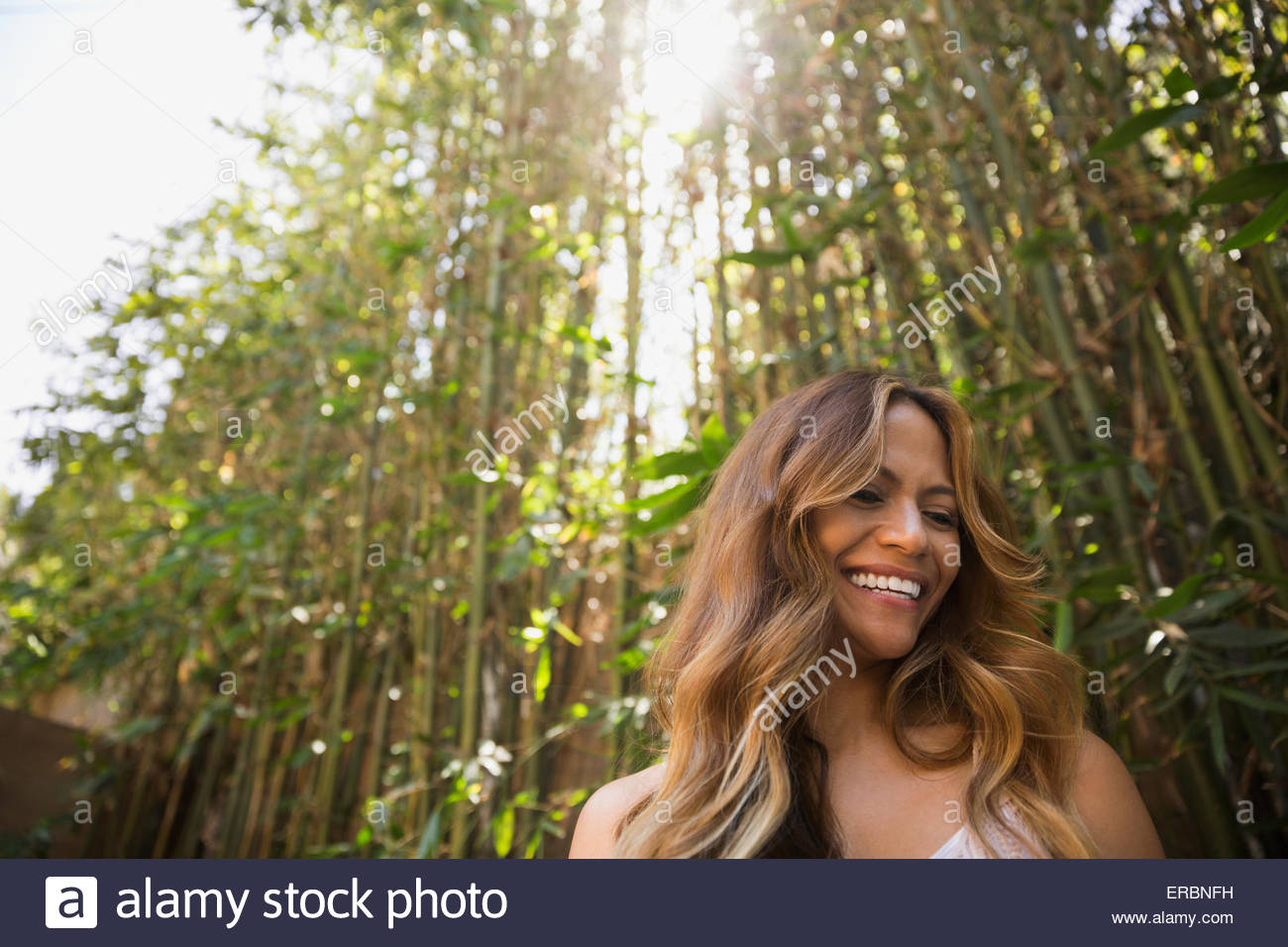 Smiling woman below bamboo looking down Stock Photo - Alamy