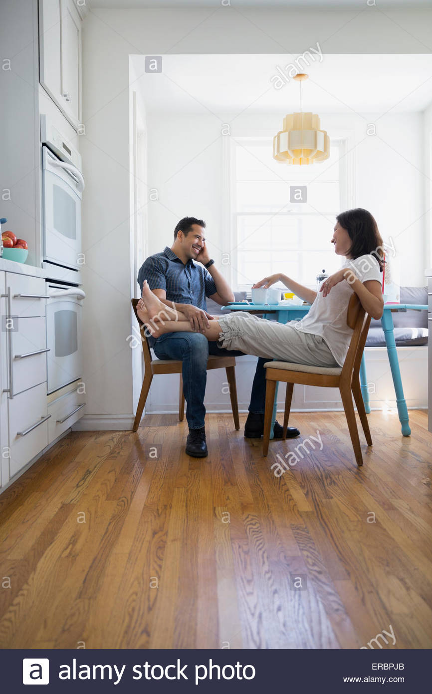 Brunette couple drinking coffee and talking kitchen table Stock Photo ...