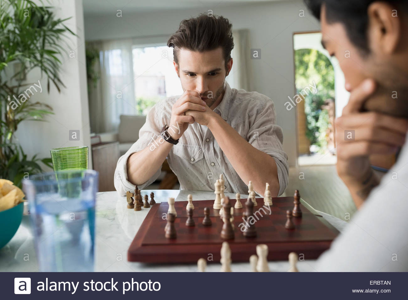 Focused men playing chess at table Stock Photo - Alamy