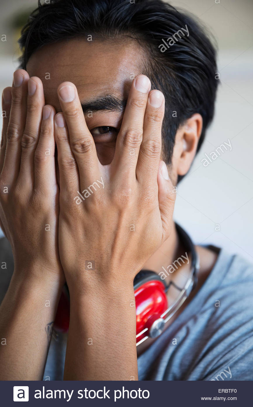 Close up portrait man peering through fingers Stock Photo - Alamy