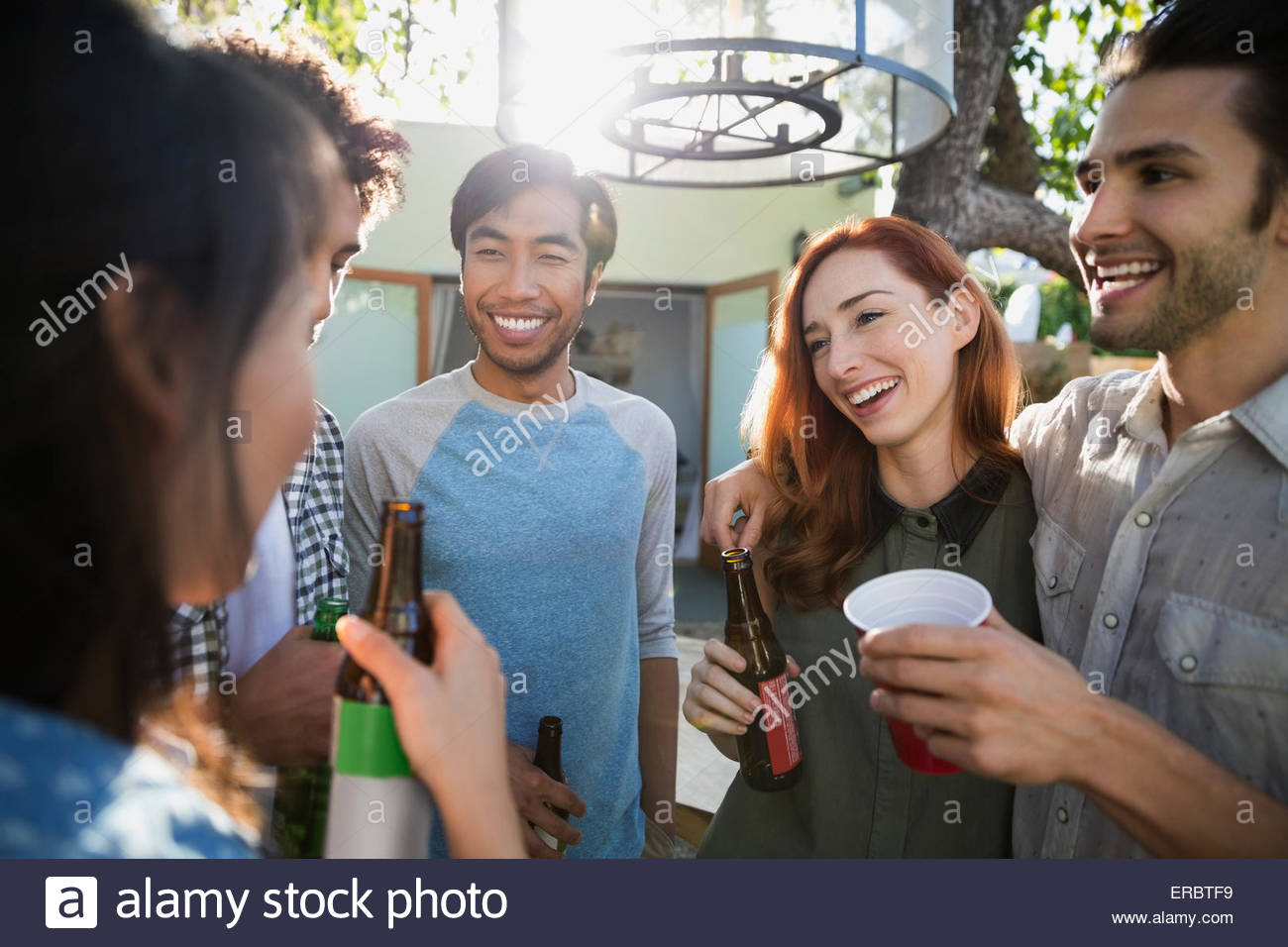Smiling friends talking drinking beer on sunny patio Stock Photo - Alamy