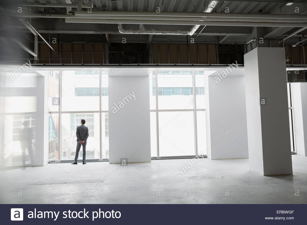 Businessman at window of empty office space Stock Photo - Alamy