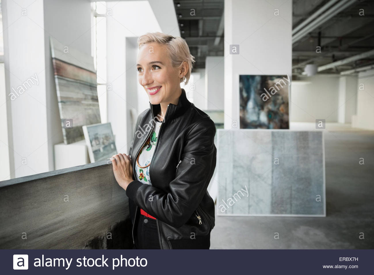 Smiling artist with paintings in art gallery Stock Photo - Alamy