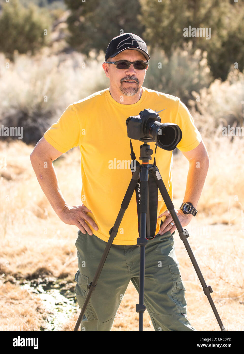 A middle aged Latin man standing behind his tripod mounted camera Stock ...