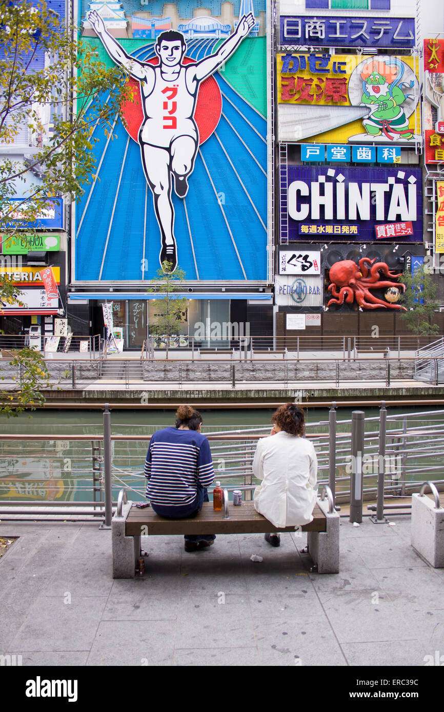 Two men sitting in front of the famous Glico man neon sign in the ...