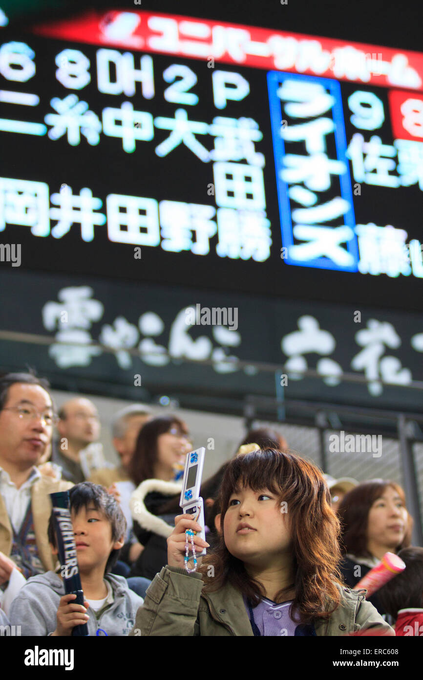 A young woman watches a game of the Nippon Ham Fighters baseball team ...