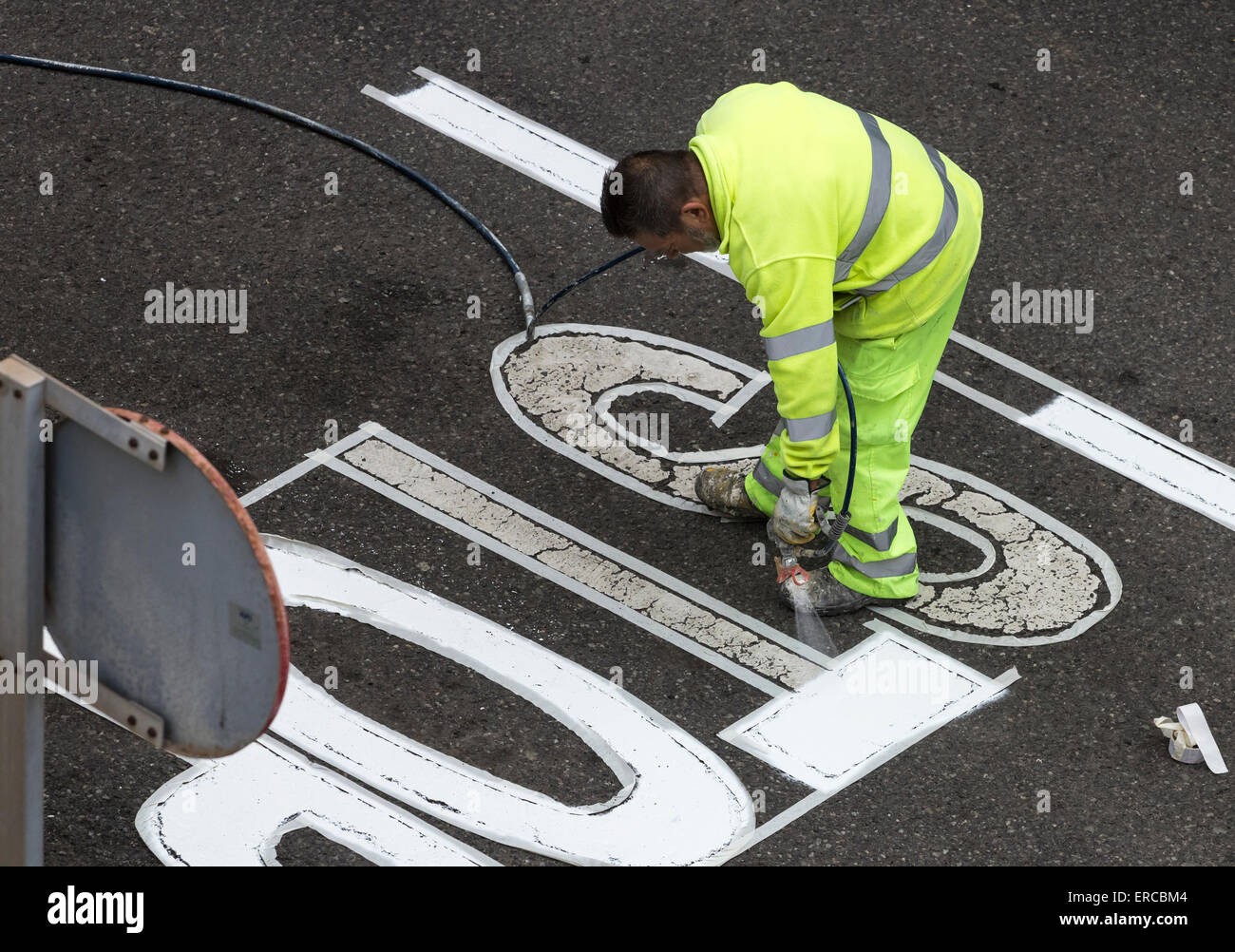 Workman repainting Stop sign on road Stock Photo - Alamy