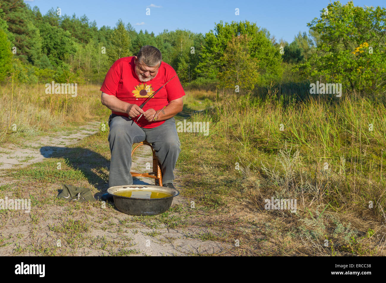 Senior man taking the small fish off the hook Stock Photo - Alamy