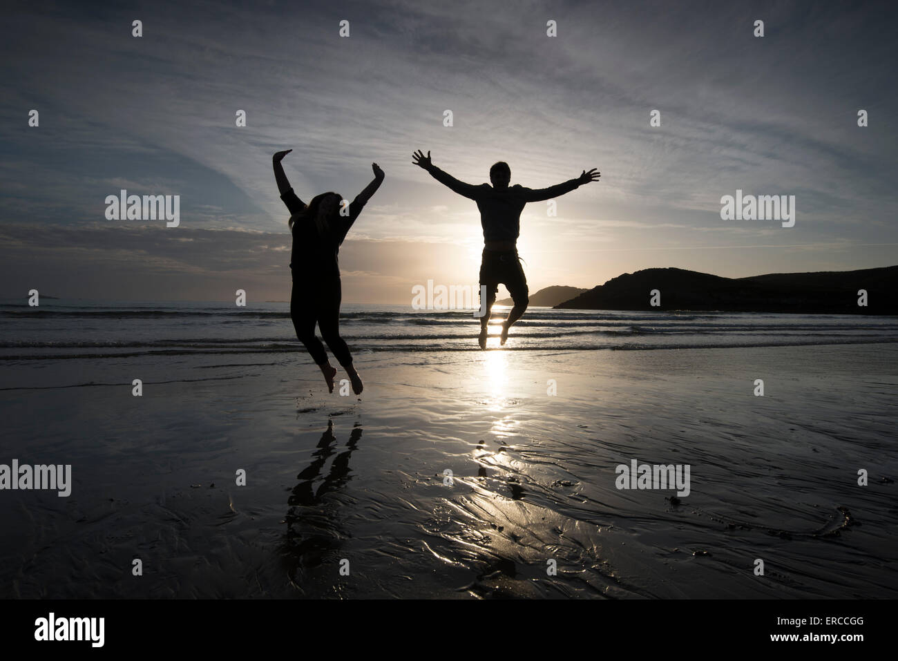 A young couple jumping in the air at sunset on Whitesands Beach in St ...