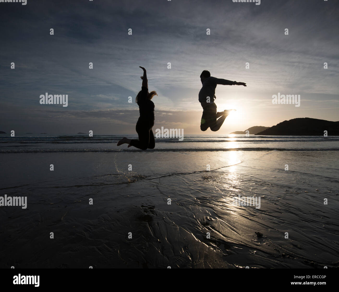 A young couple jumping in the air at sunset on Whitesands Beach in St ...