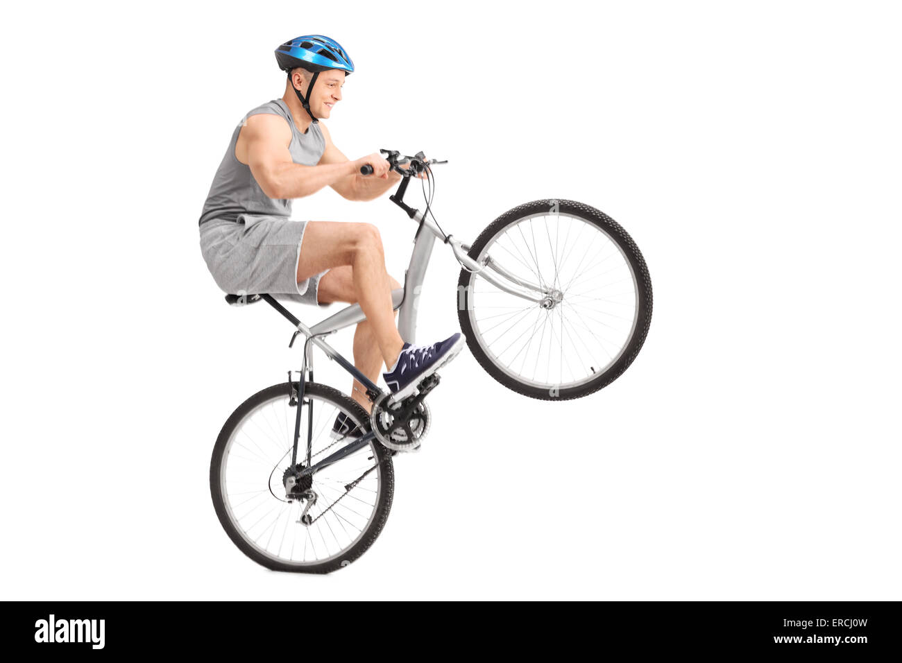Studio shot of a joyful young biker doing a wheelie with his bicycle ...