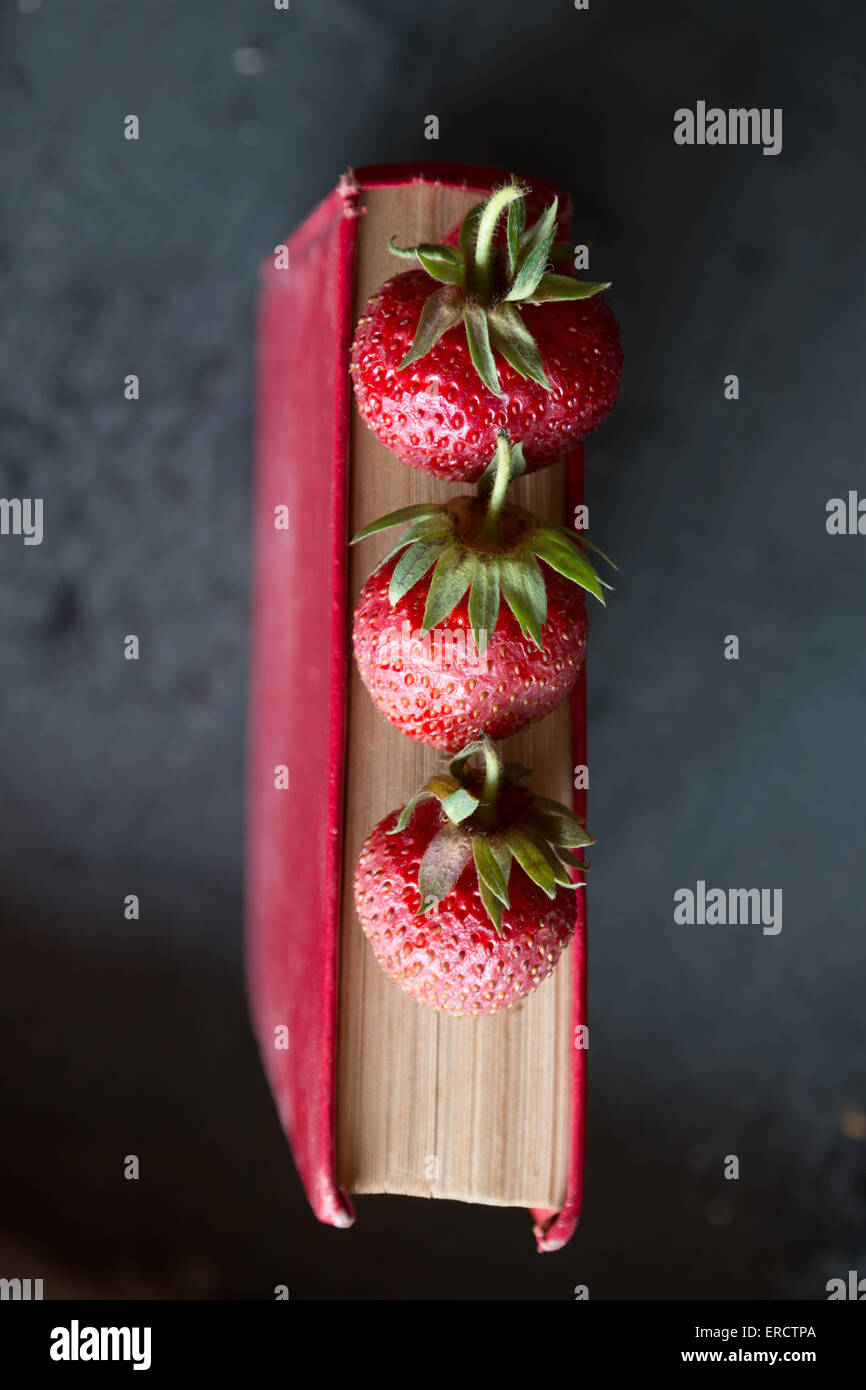 Strawberries and red cook book on a dark table Stock Photo - Alamy