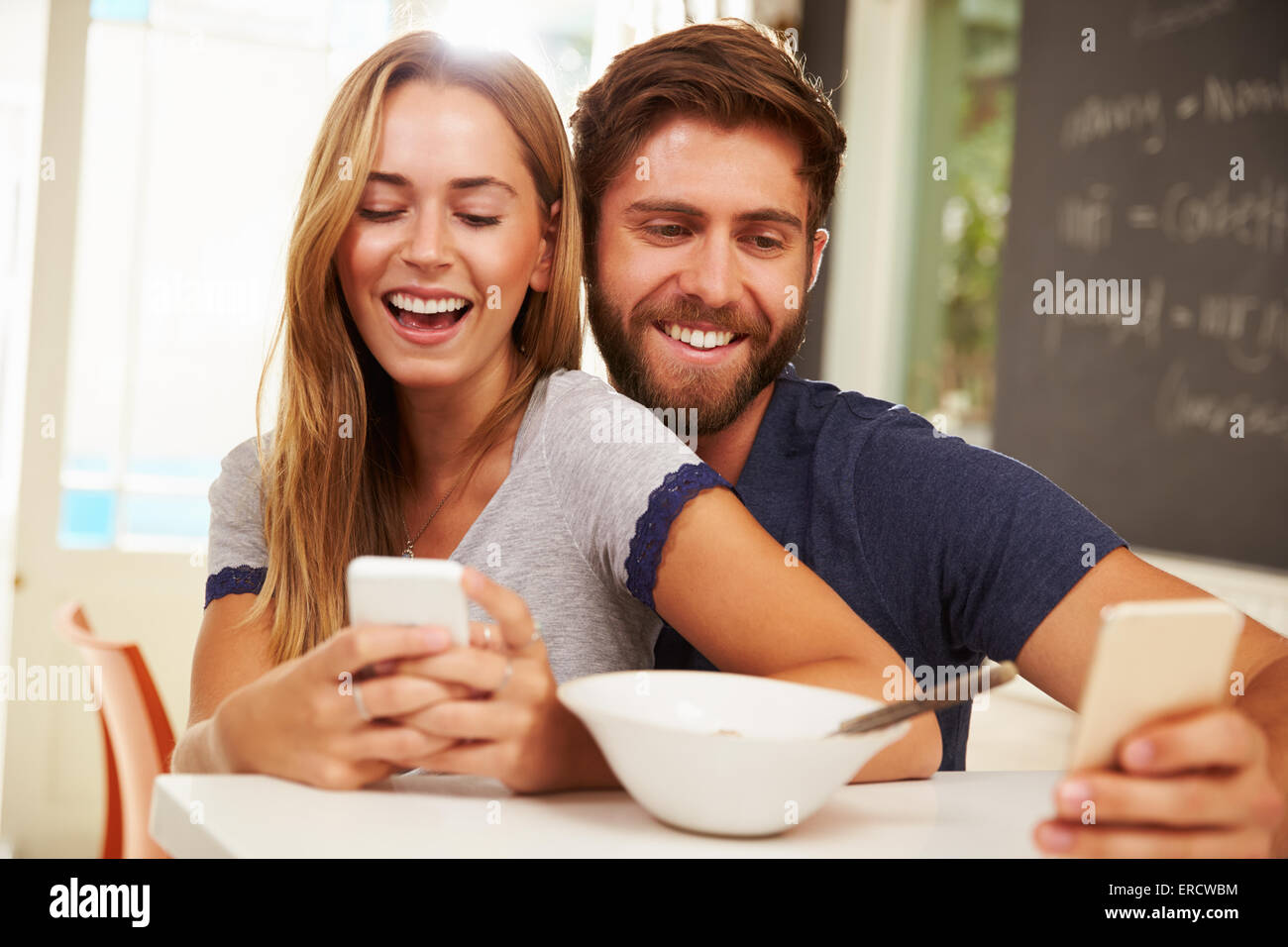 Young Couple Eating Breakfast Whilst Using Mobile Phones Stock Photo ...