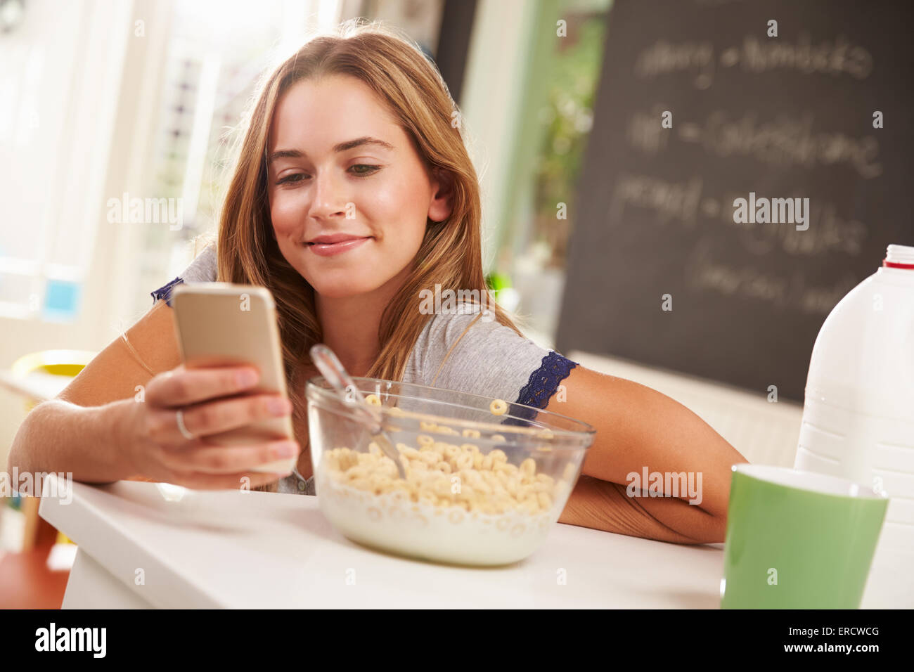 Young Woman Eating Breakfast Whilst Using Mobile Phone Stock Photo - Alamy