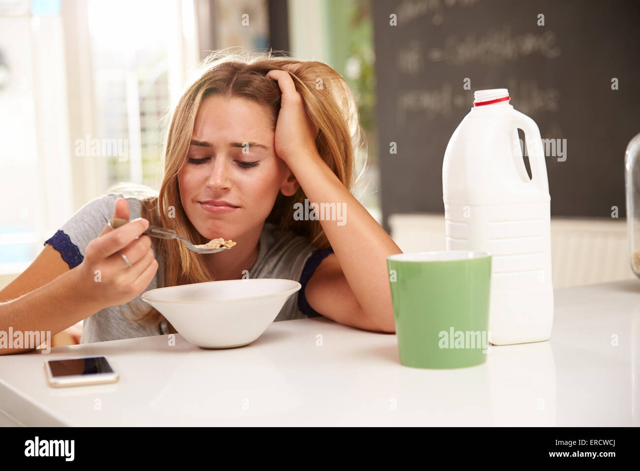 Young Woman Eating Breakfast Whilst Using Mobile Phone Stock Photo - Alamy