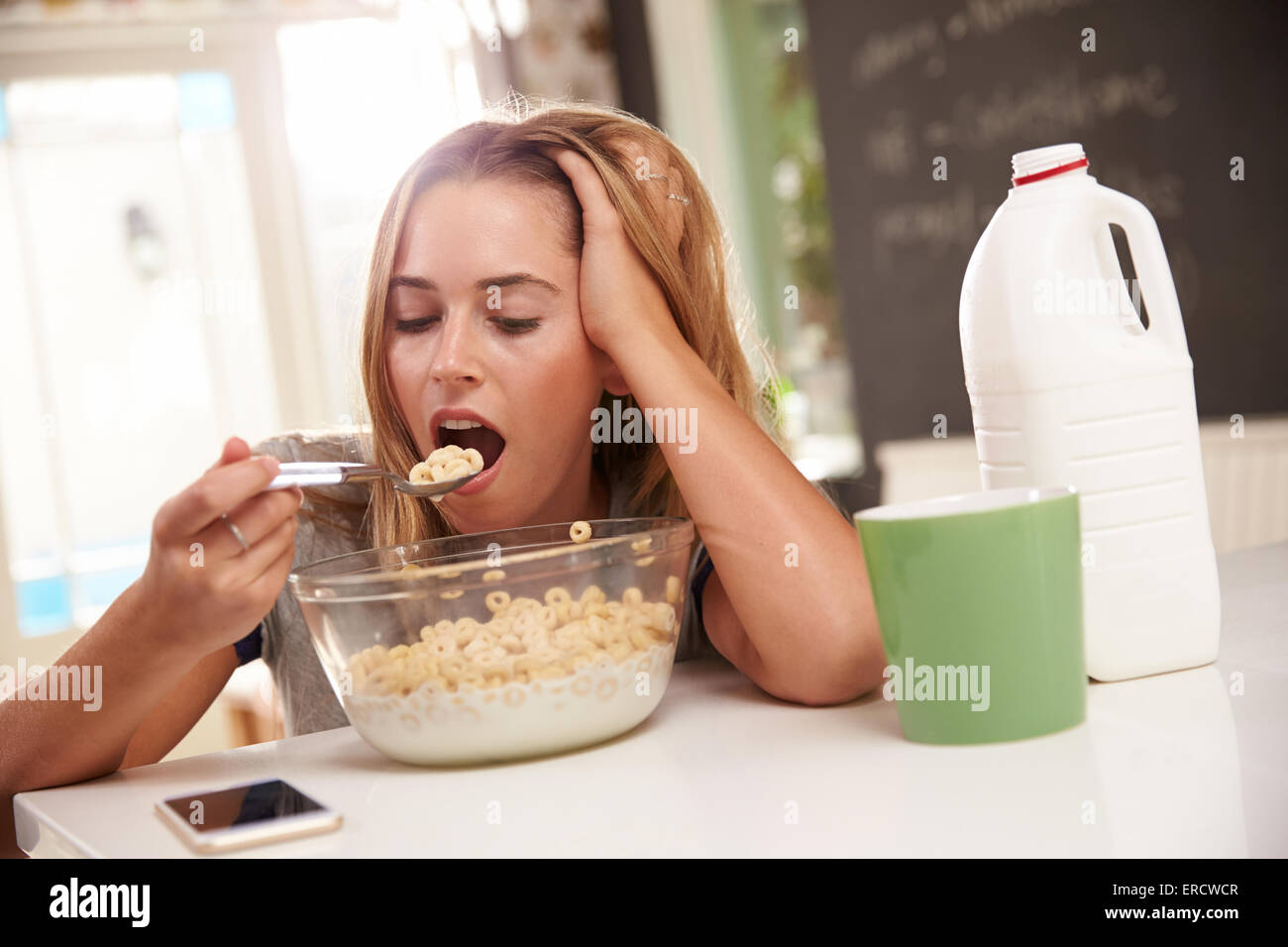 Young Woman Eating Breakfast Whilst Using Mobile Phone Stock Photo - Alamy