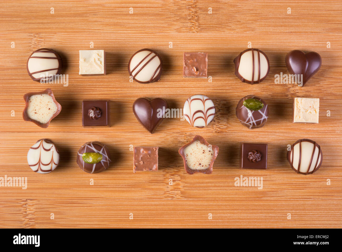 Assorted chocolate candies arranged in rows on a wooden surface Stock ...