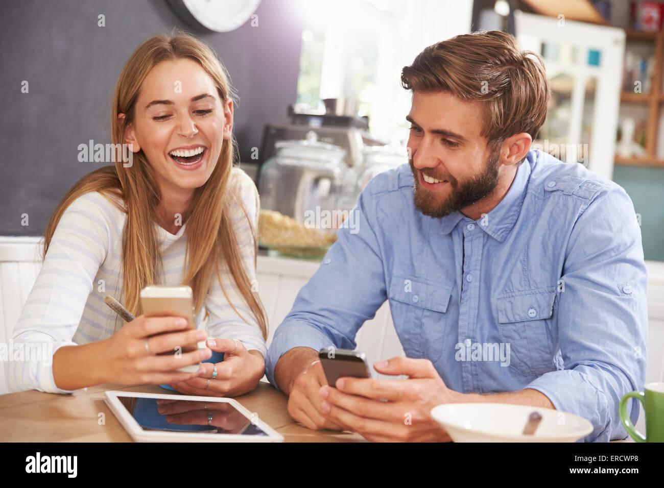 Young Couple Eating Breakfast Whilst Using Mobile Phones Stock Photo ...
