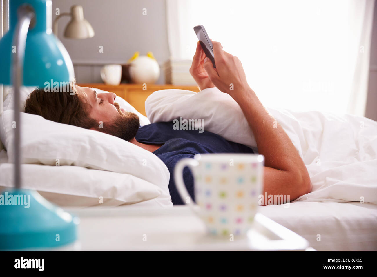 Man Lying In Bed Checking Mobile Phone Stock Photo - Alamy