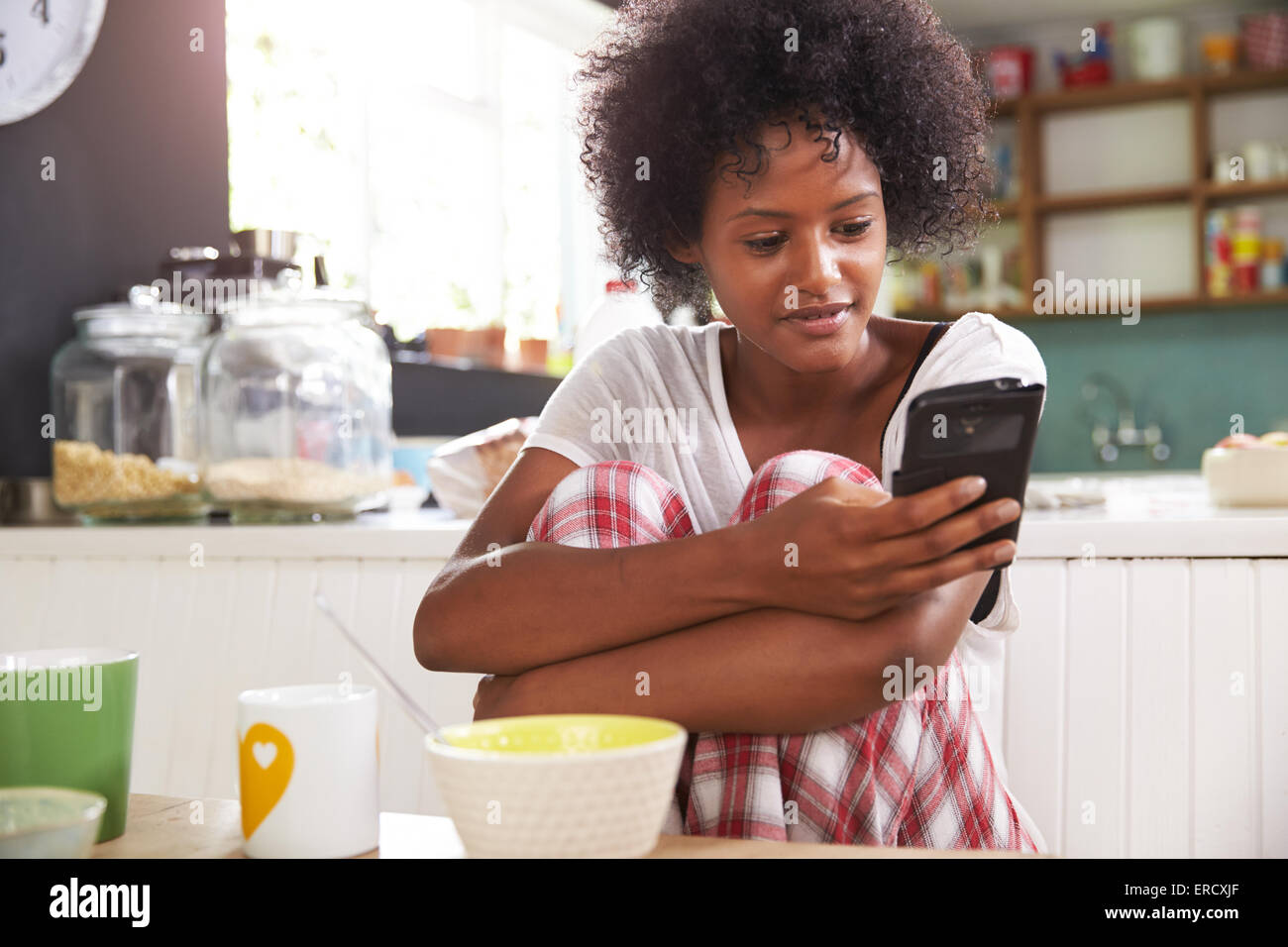 Young Woman Eating Breakfast Whilst Using Mobile Phone Stock Photo - Alamy