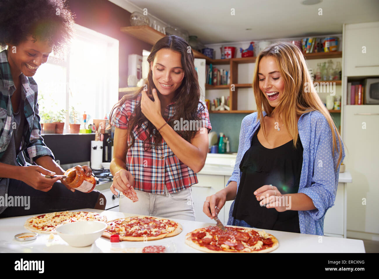 Three Female Friends Making Pizza In Kitchen Together Stock Photo - Alamy