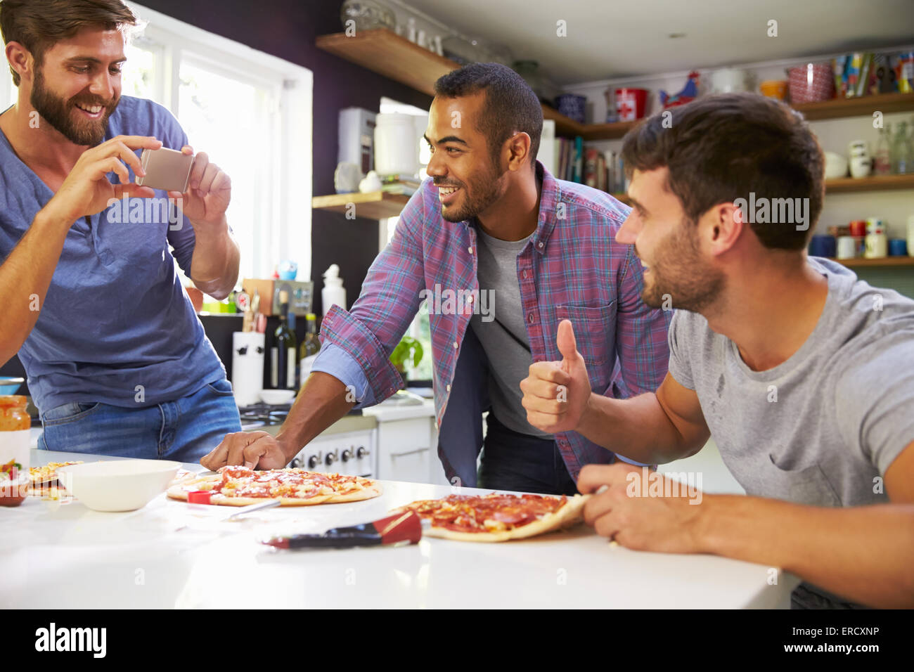 Three Male Friends Making Pizza In Kitchen Together Stock Photo - Alamy