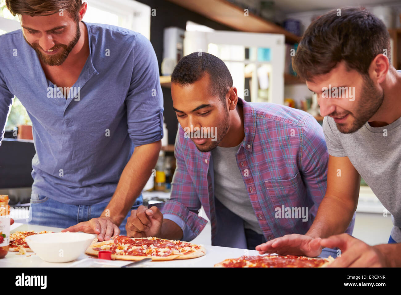 Three Male Friends Making Pizza In Kitchen Together Stock Photo - Alamy