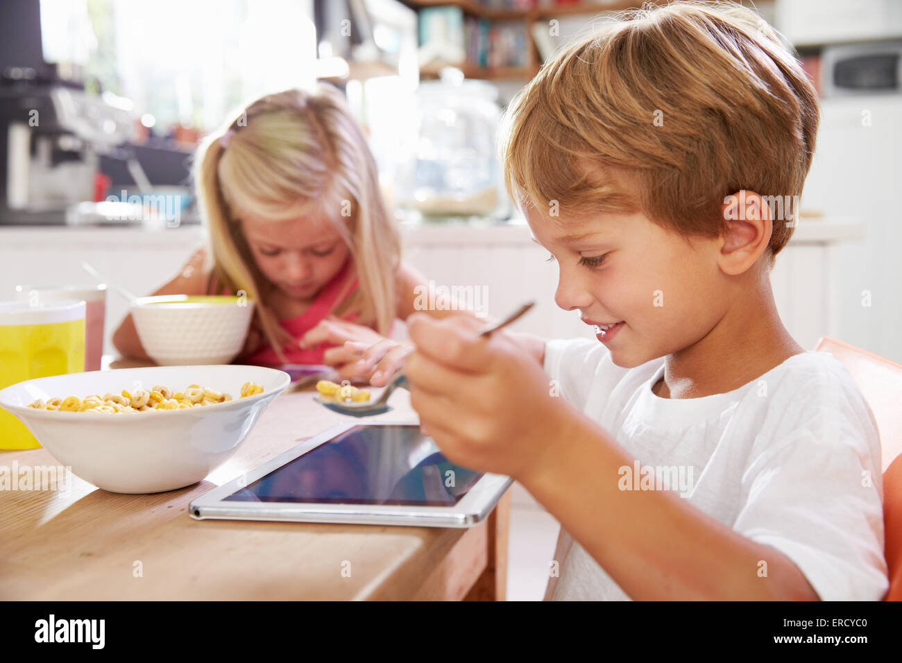 Children Eating Breakfast Whilst Using Digital Tablet Stock Photo - Alamy